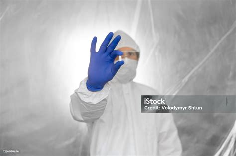 흰색 보호복 의료 용 마스크 및 고무 장갑을 착용한 의사가 코로나바이러스 전염병 위협의 약물로 흰 약을 들고 있습니다 전염병