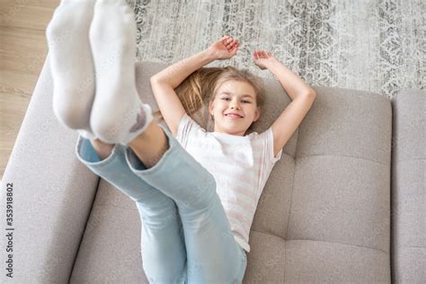 Preteen Girl Lying On Couch With Her Feet Raising Up High 素材庫相片 Adobe